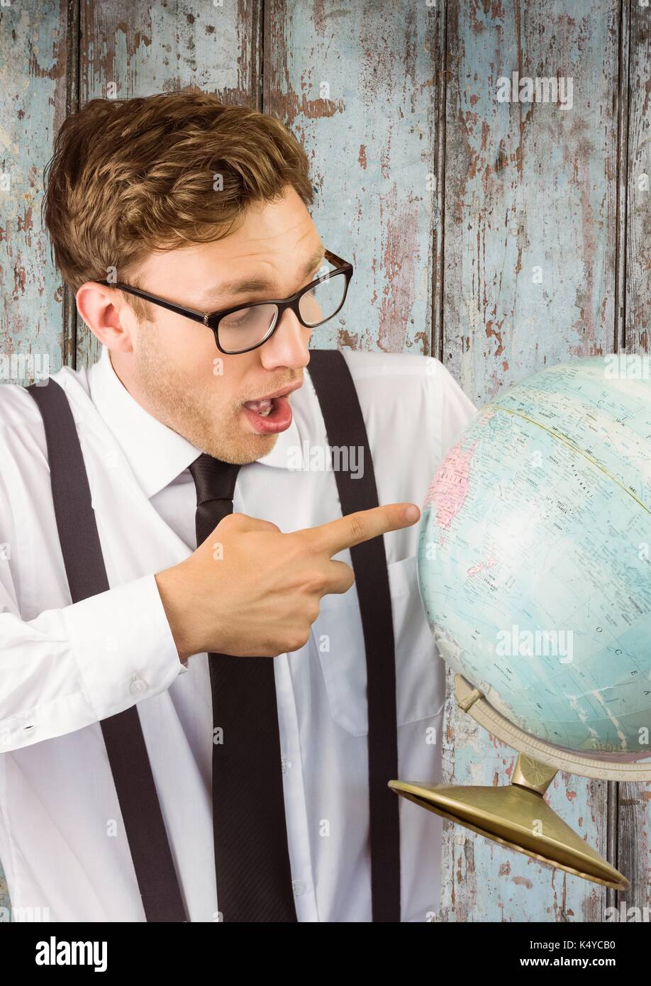 Digital composite of Nerd man pointing at globe against wood panel ...