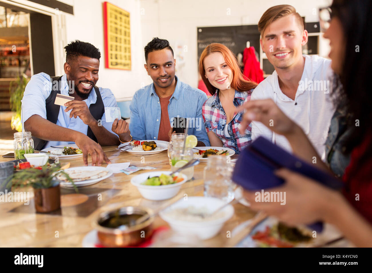 happy friends with money paying bill at restaurant Stock Photo - Alamy