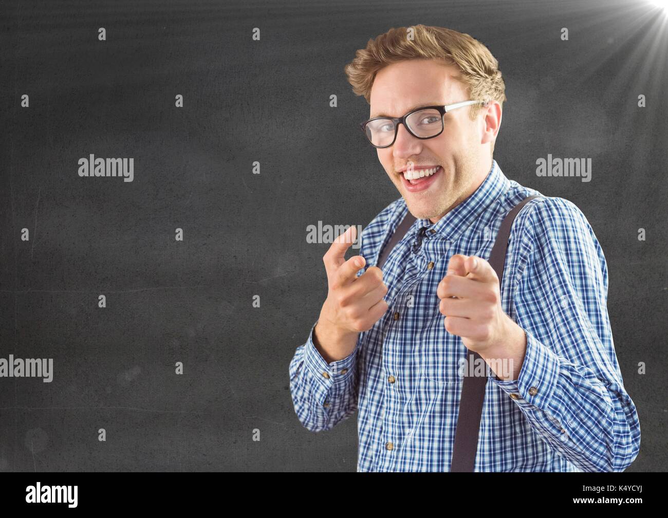 Digital composite of Nerd man pointing against grey wall with flare ...