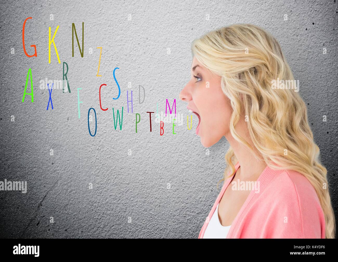 Digital composite of young woman shouting with colour letters coming up ...