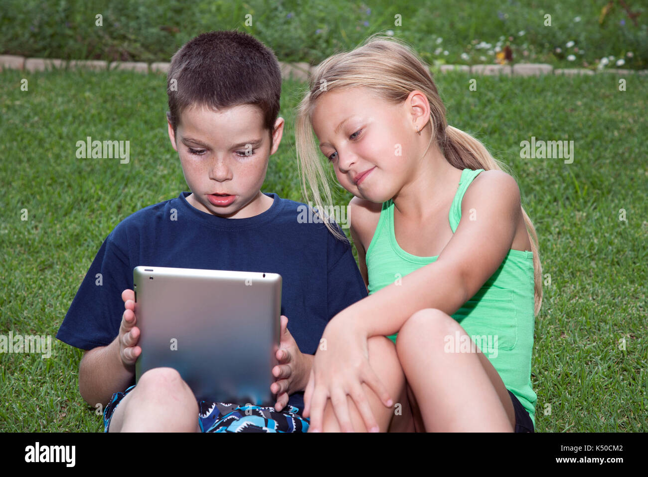 Two kids playing on an iPad Stock Photo - Alamy