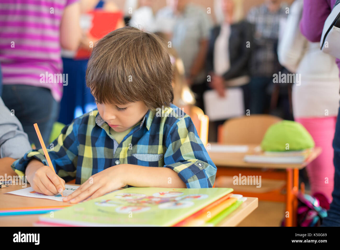 Young first grade student sitting at desk on his first day at school in ...