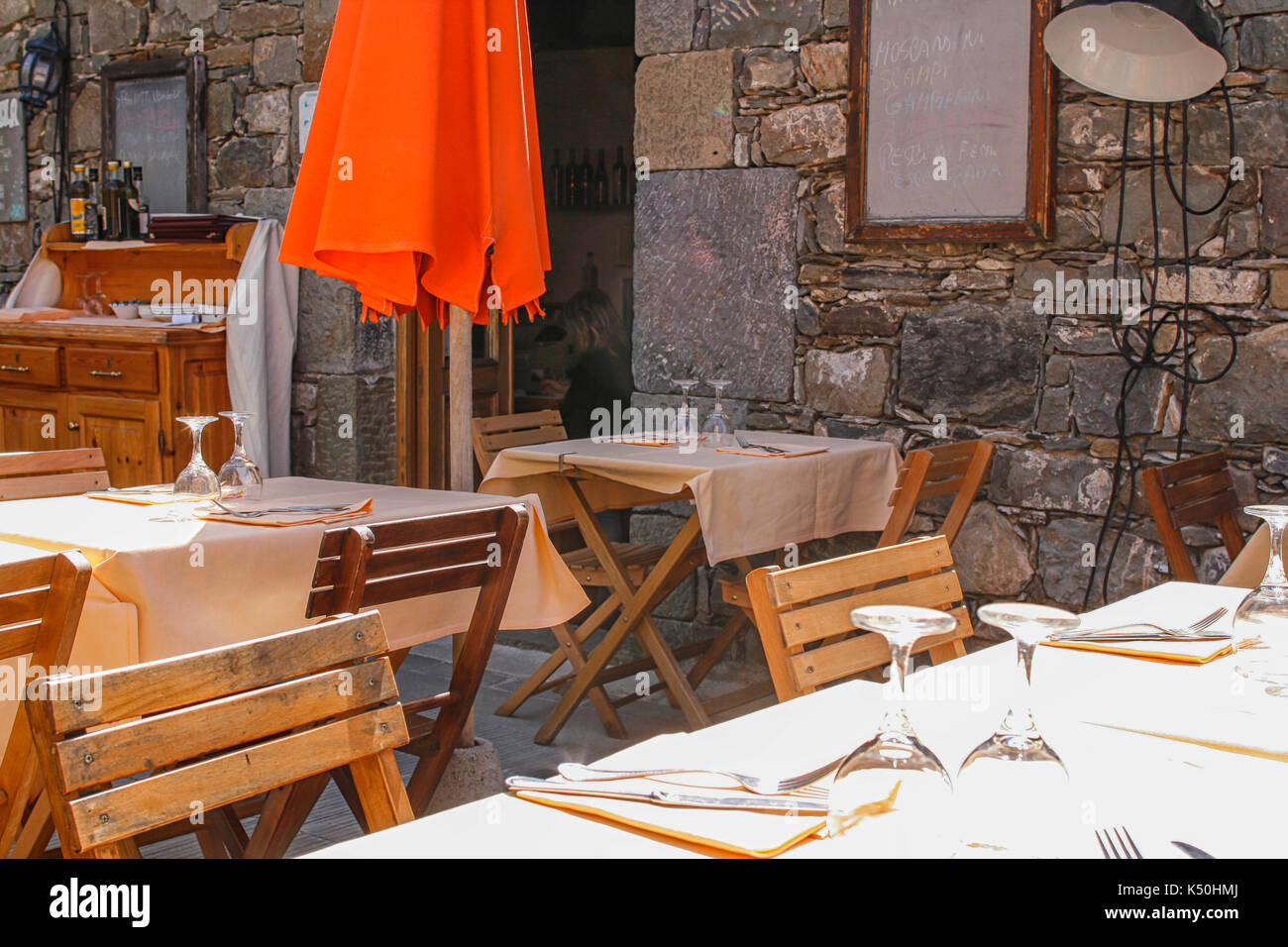 Typical rural outdoor restaurant in Italy with wooden chairs on street ...