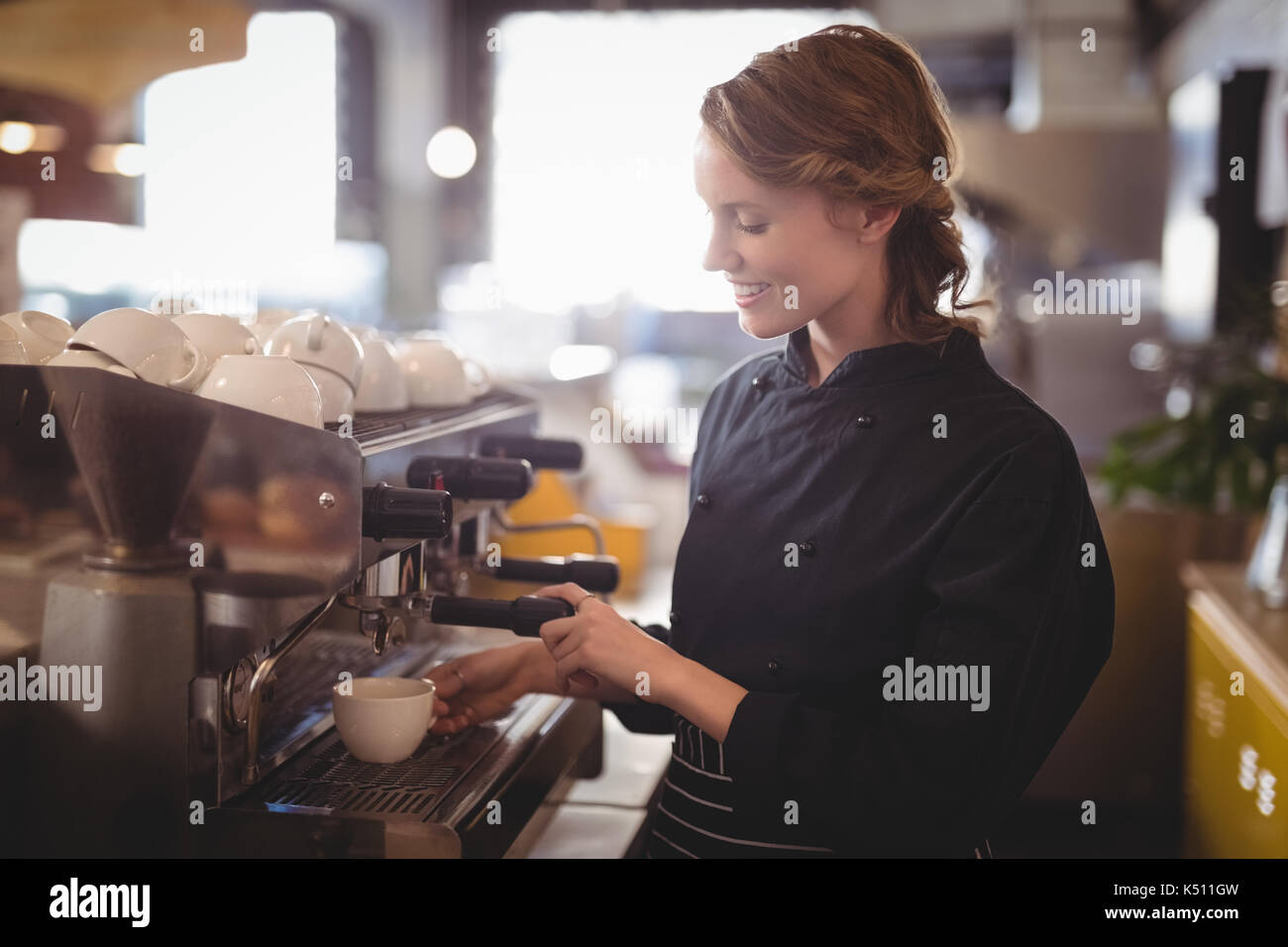 Smiling young waitress using espresso maker at coffee shop Stock Photo ...