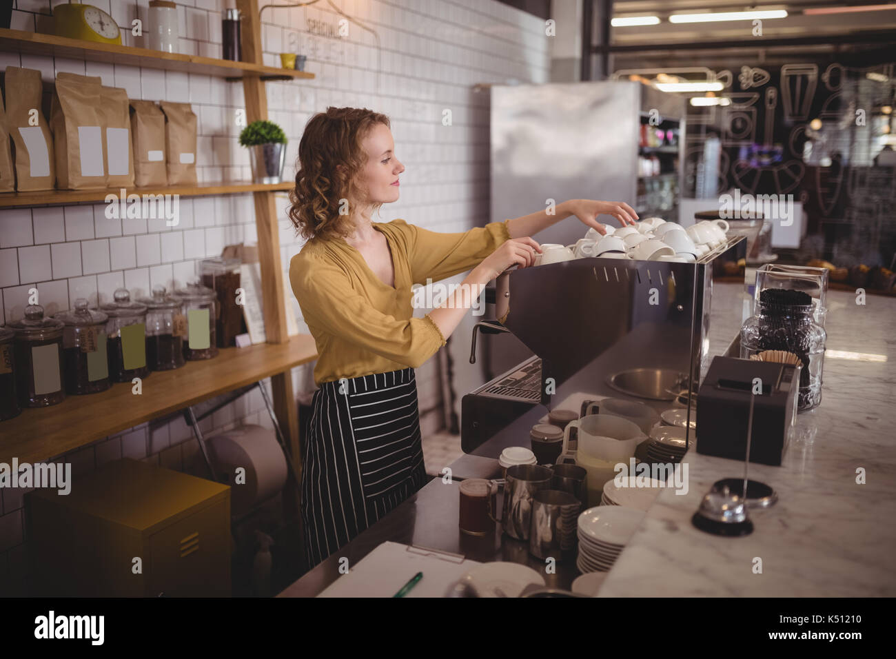 Young waitress arranging cups at counter in coffee shop Stock Photo - Alamy