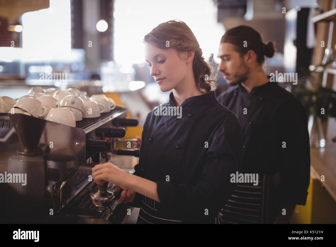Young wait staff using espresso maker standing in coffee shop Stock ...