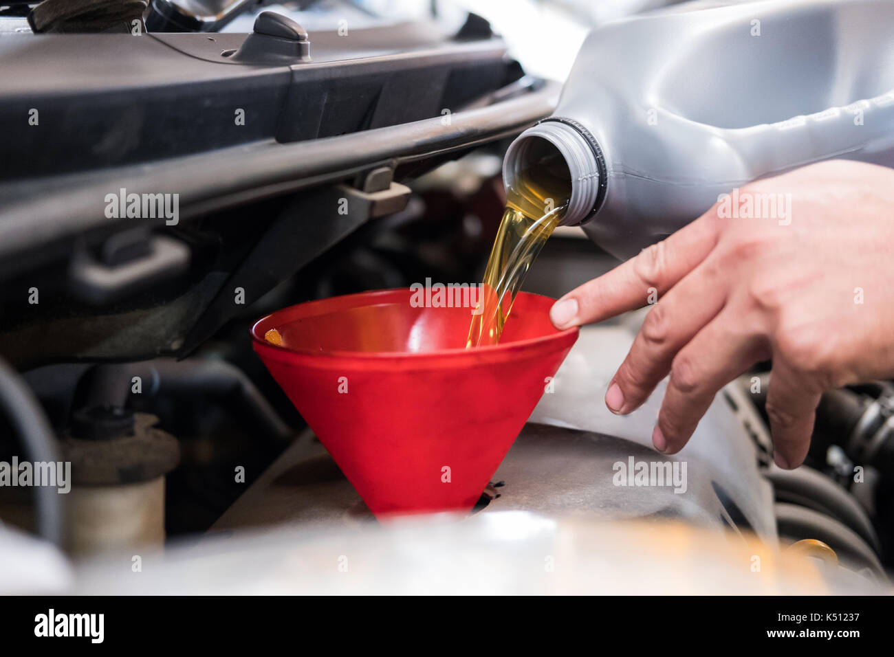 mechanic pouring oil to vehicle engine. serviceman changing motor oil ...