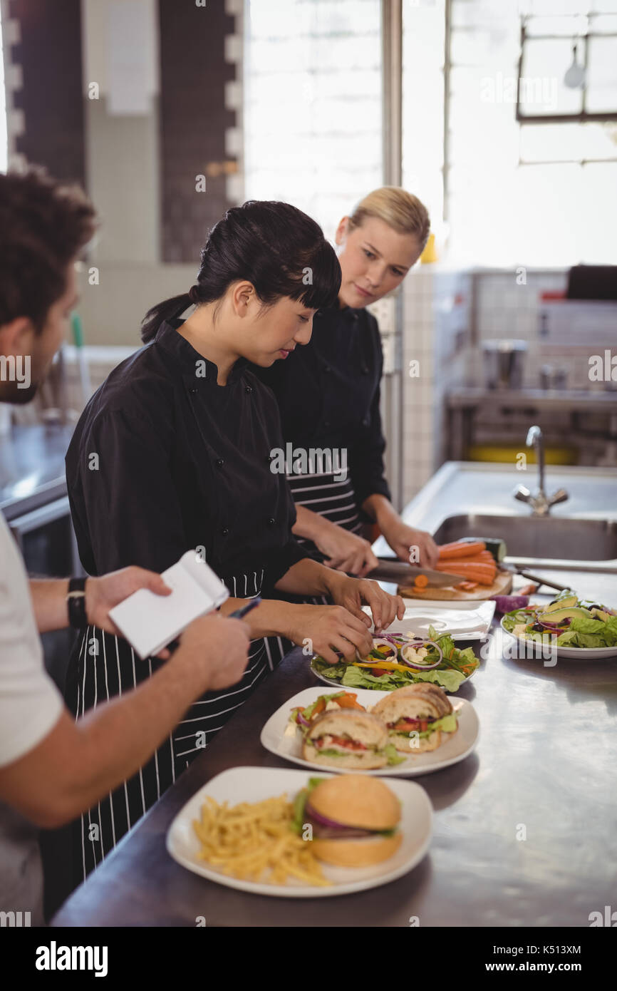 Young female chefs preparing food on kitchen counter at cafeteria Stock ...