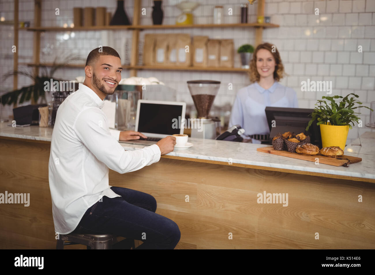 Portrait of smiling male owner and waitress at counter in coffee shop ...