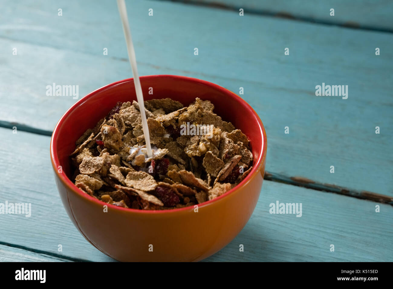 Close-up of pouring milk into bowl of wheat flakes Stock Photo - Alamy
