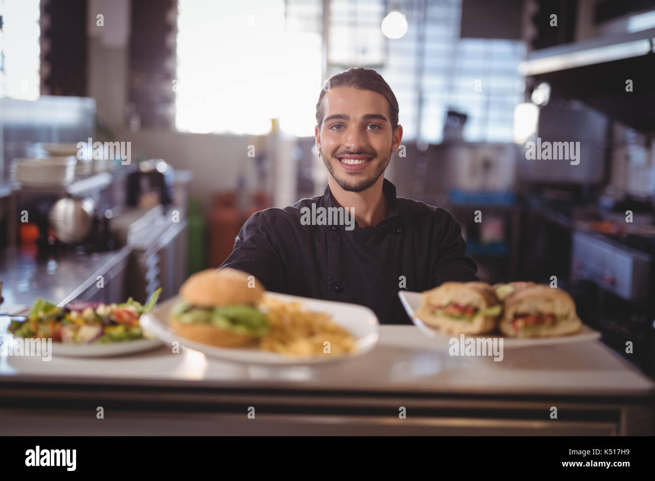 Portrait of smiling waiter serving fresh food at counter in coffee shop ...