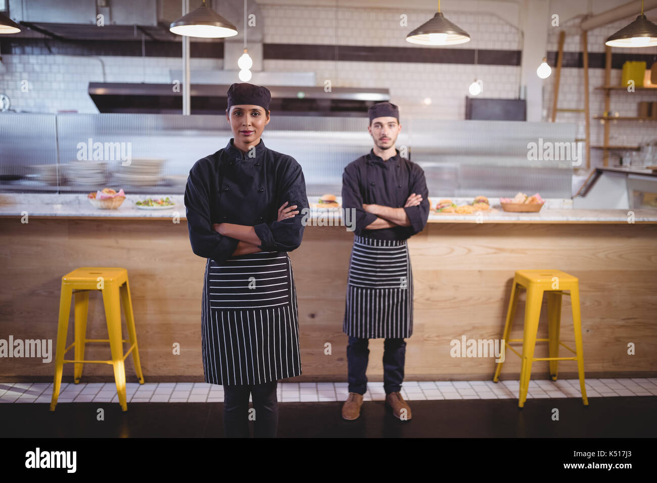 Portrait of confident young wait staff standing with arms crossed ...