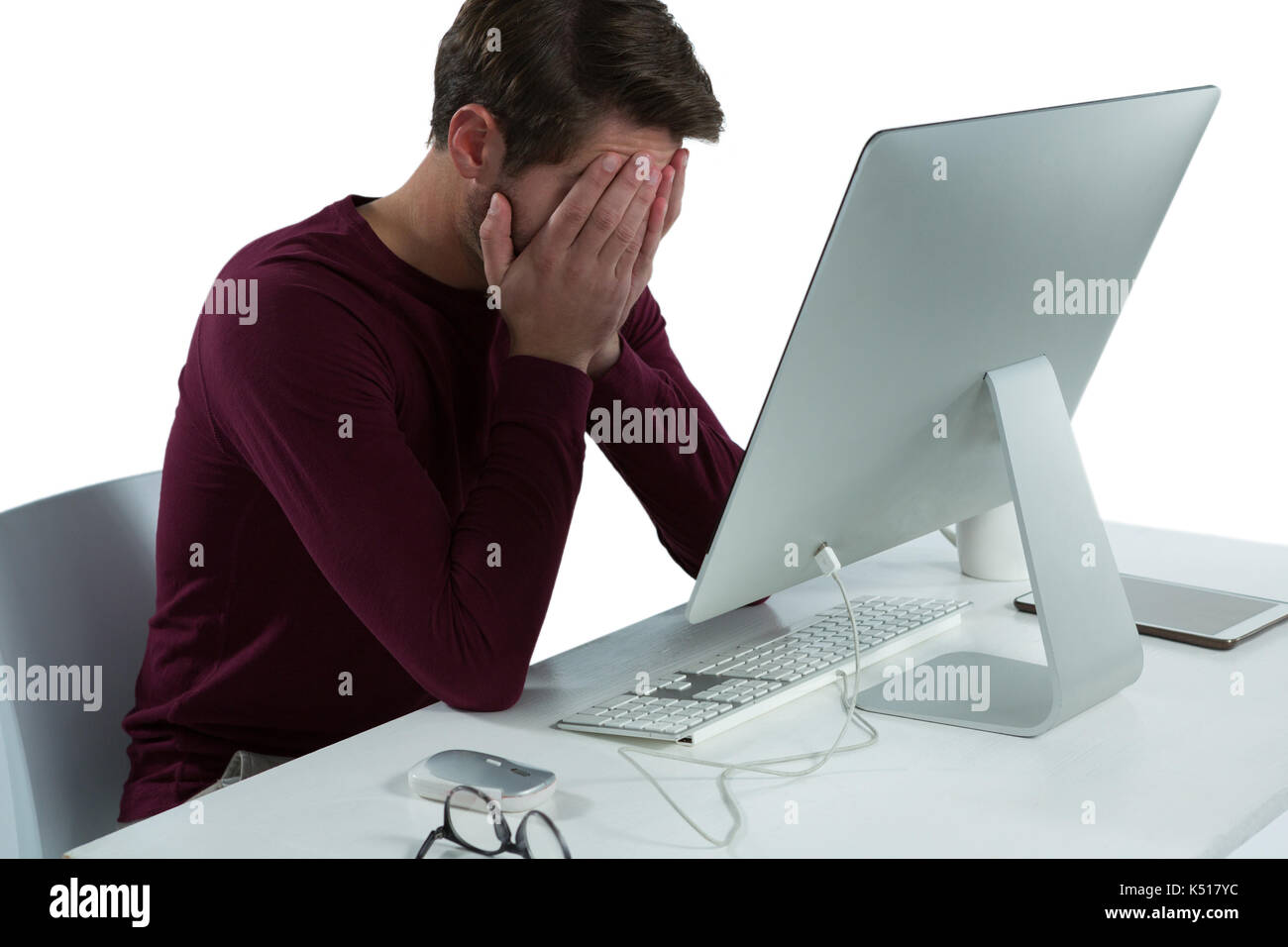 Stressed man sitting at desk against white background Stock Photo - Alamy