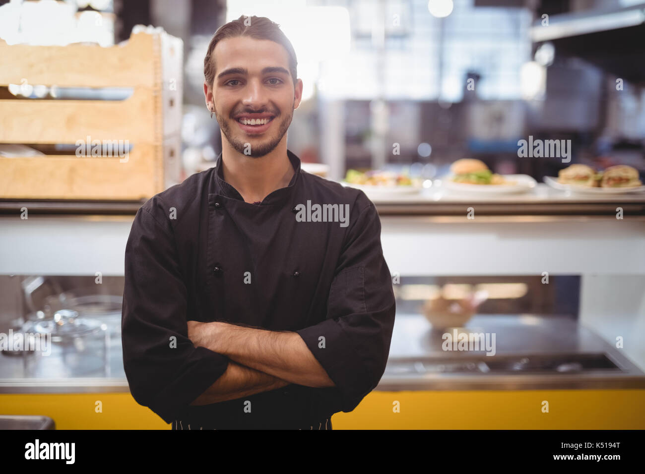 Portrait of smiling young waiter standing against counter in coffee ...