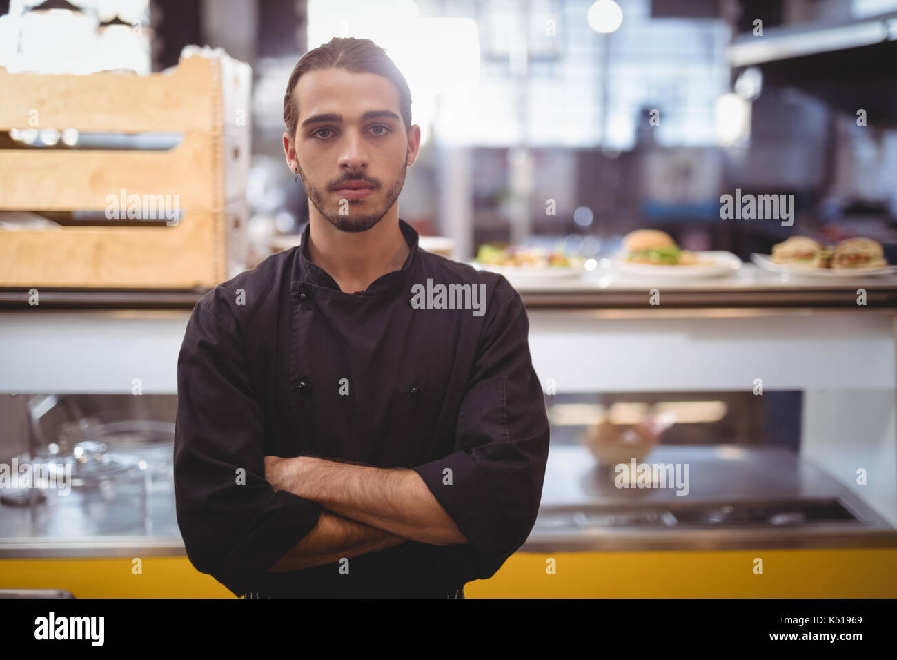 Portrait of confident young waiter standing against counter in coffee ...