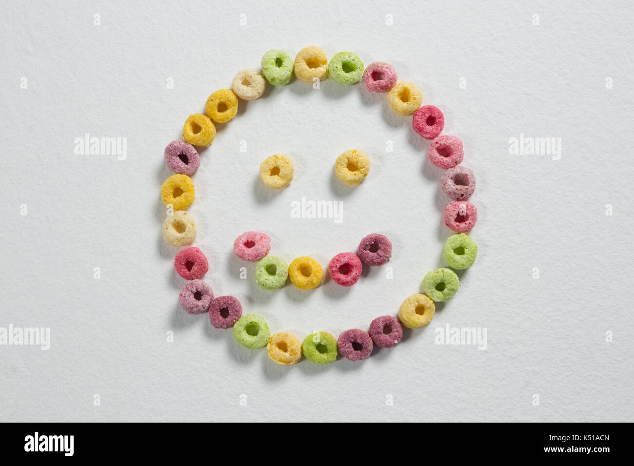 Froot loops forming a smiley face on white background Stock Photo - Alamy