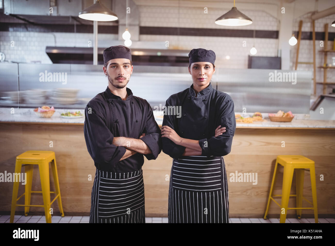 Portrait of confident young wait staff in black uniform standing with ...