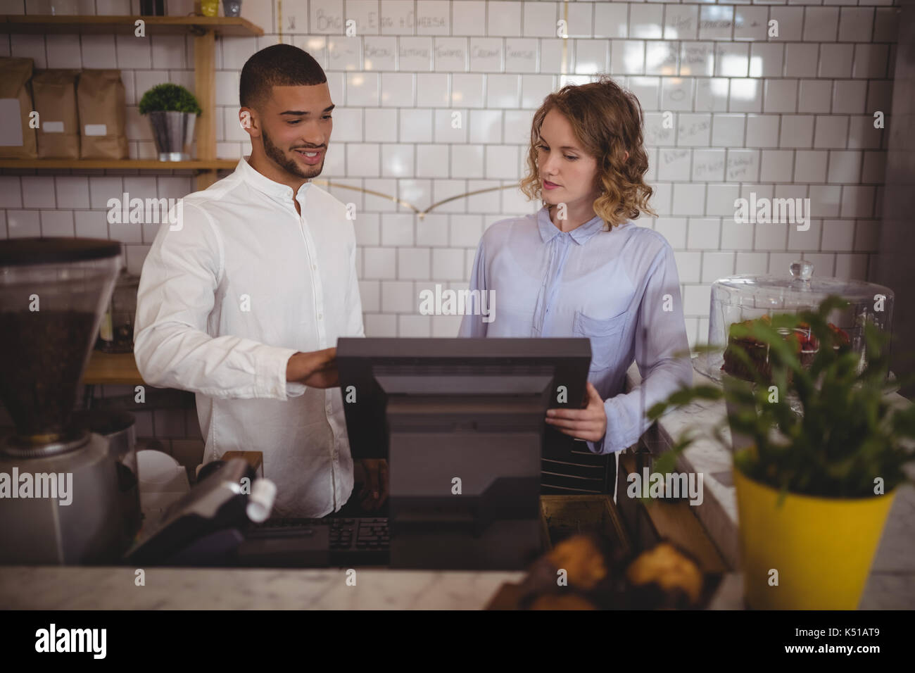 Male owner with waitress using computer at counter in coffee shop Stock ...