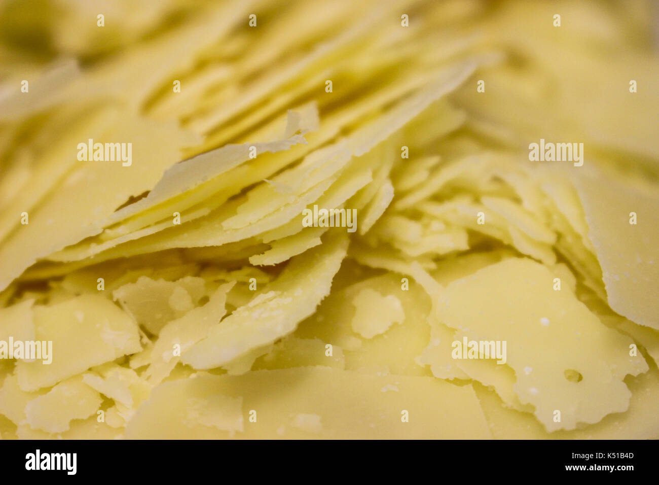 Parmesan slices in the close up background Stock Photo - Alamy
