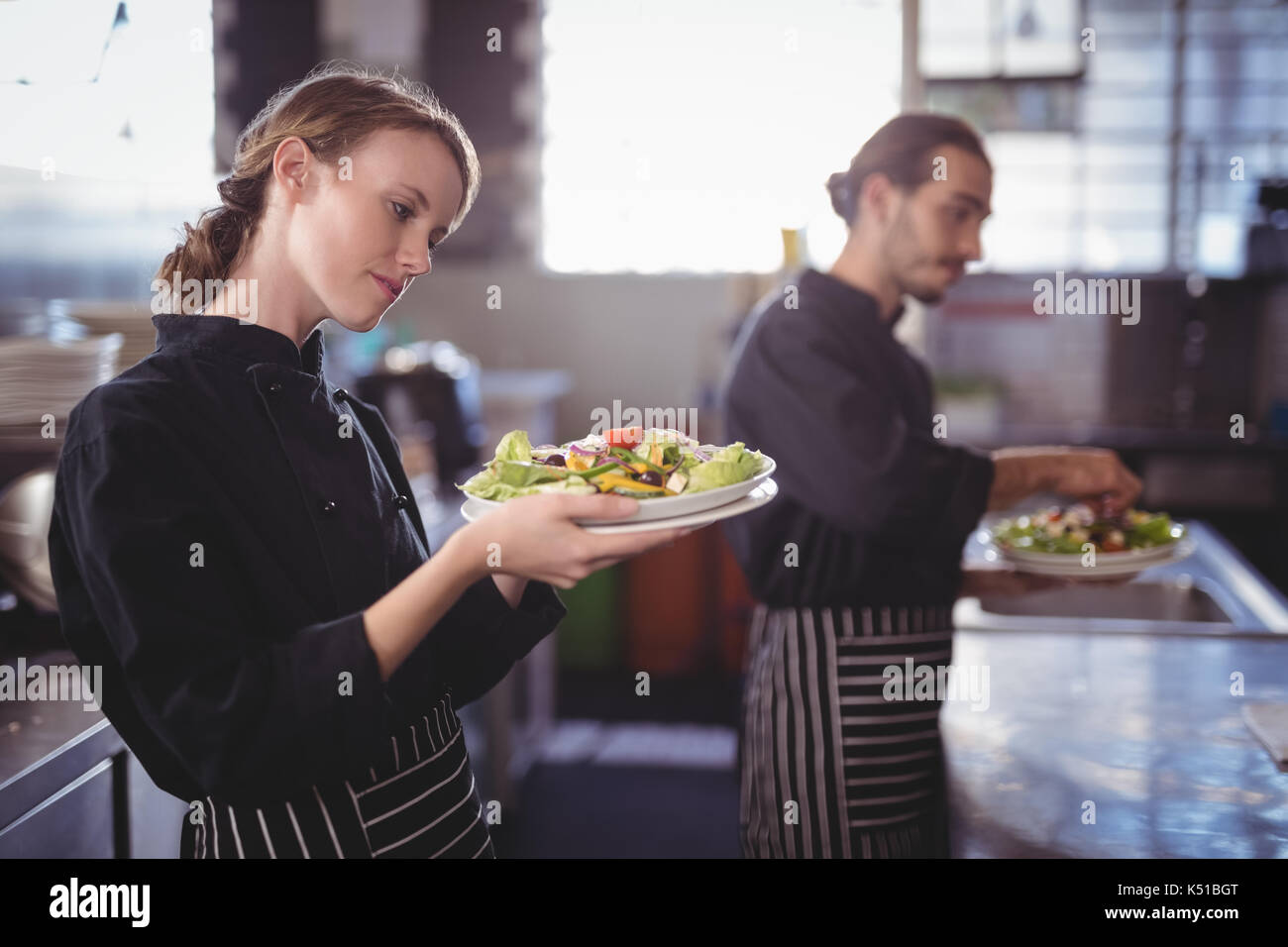 Young wait staff holding fresh salad plates while standing in ...