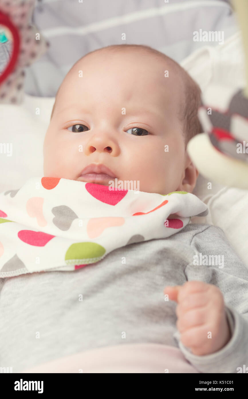 Cute newborn baby girl in a rocking seat with toys hanging above her ...