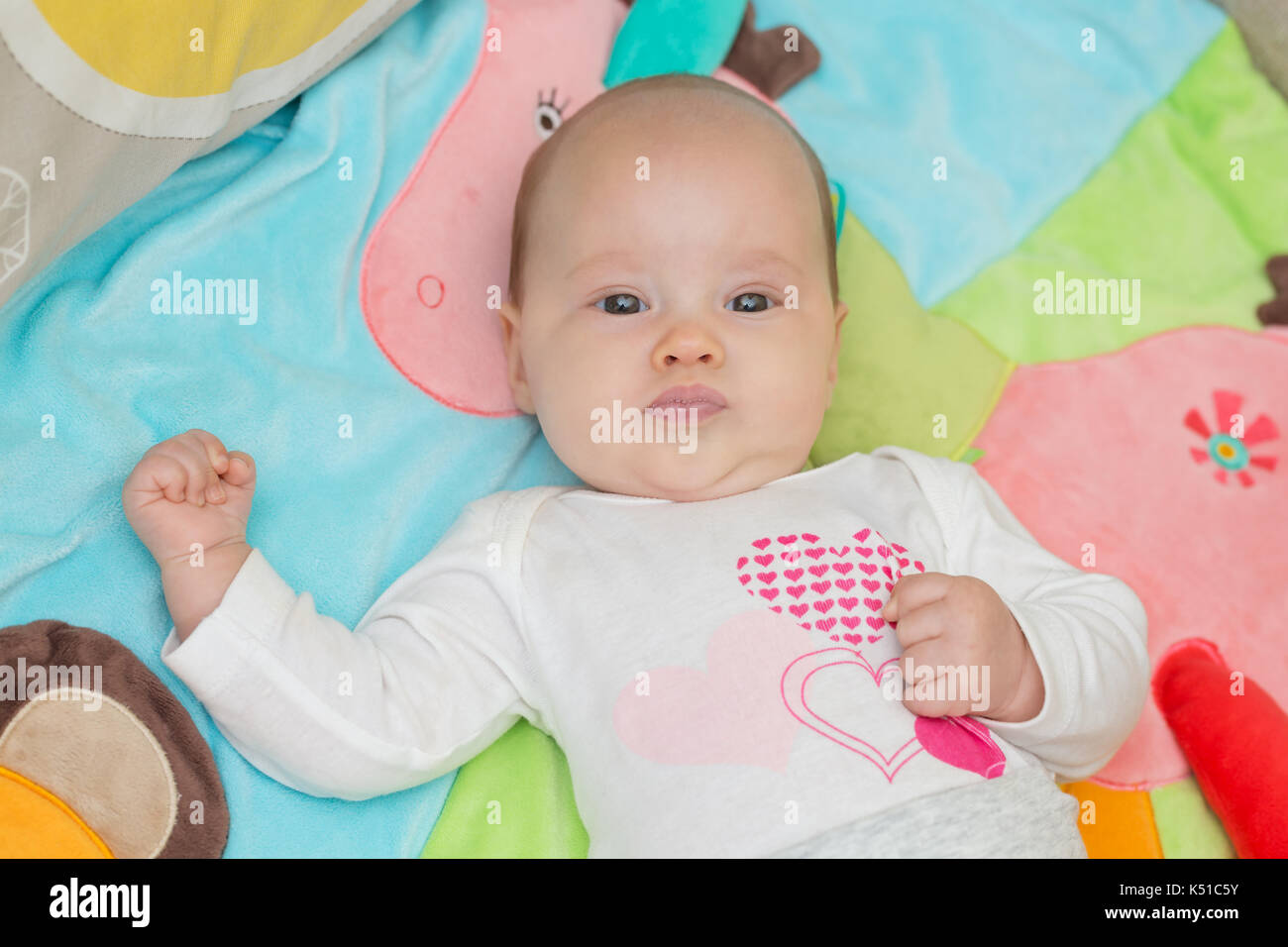 Cute newborn baby laying on a colorful playground mat Stock Photo - Alamy