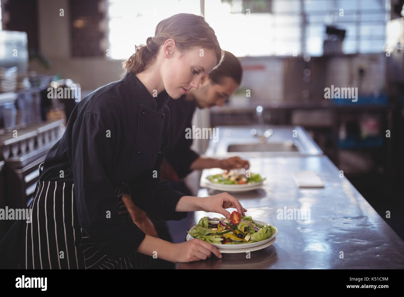 Side view of young wait staff preparing fresh salad plates while ...