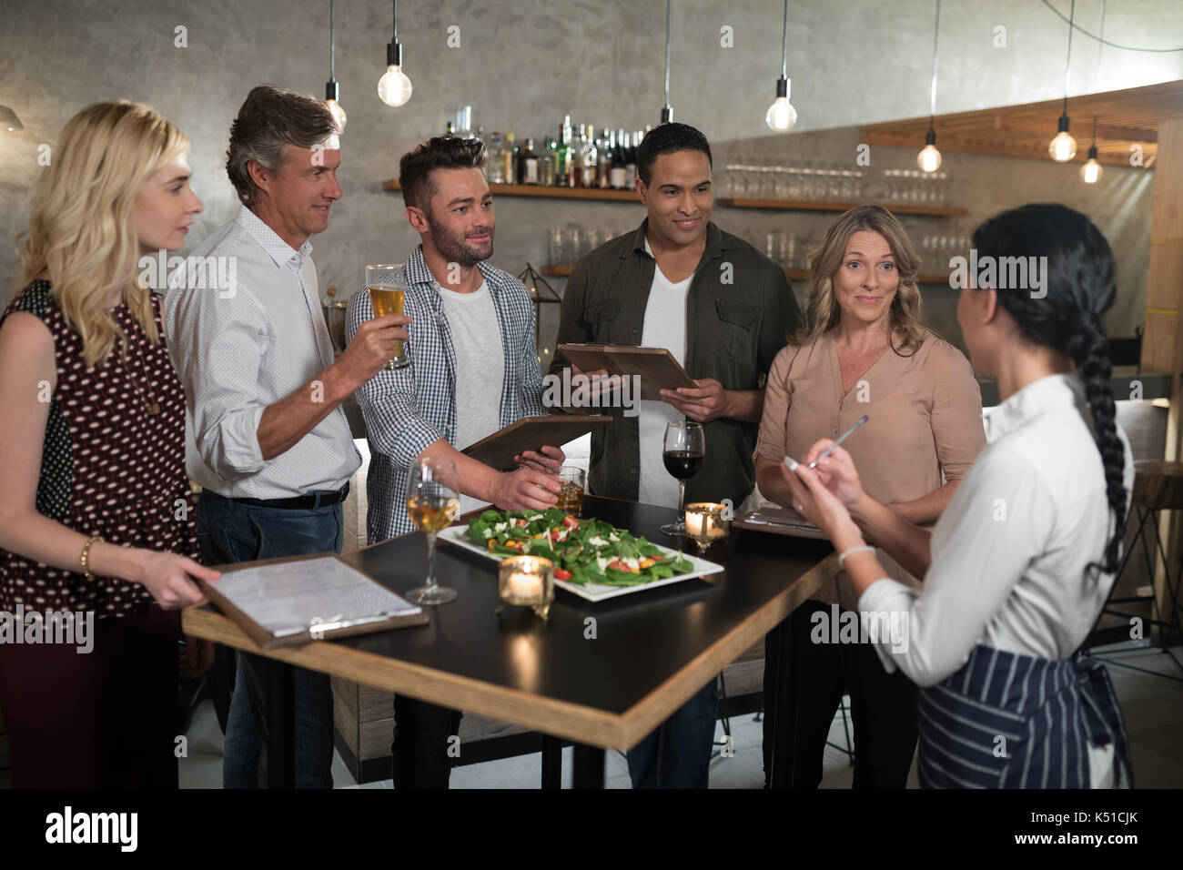 Group of friends giving order to waitress in restaurant Stock Photo - Alamy
