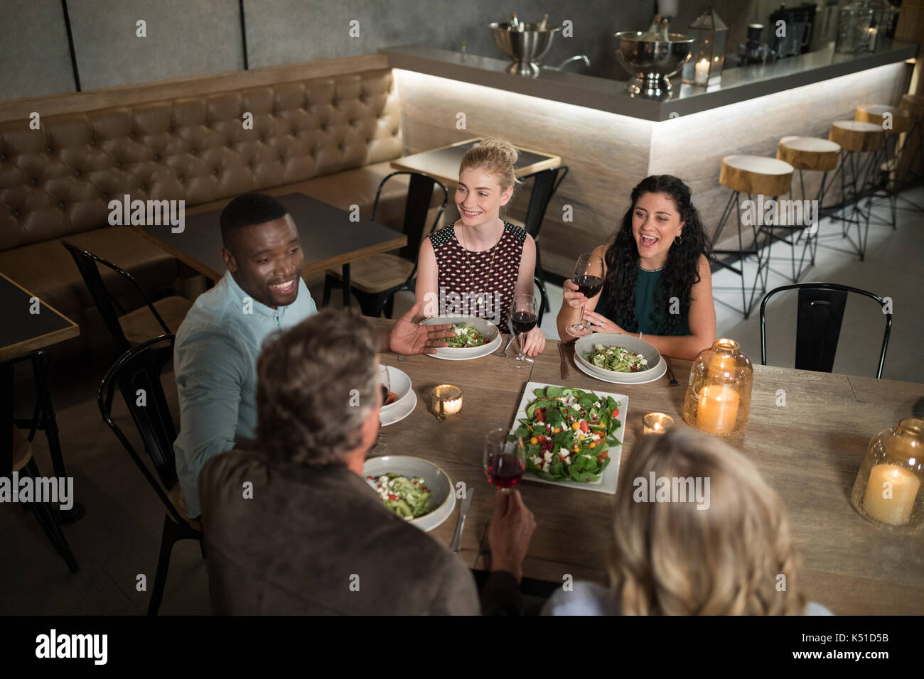 Group of friends interacting with each other while dining in restaurant ...