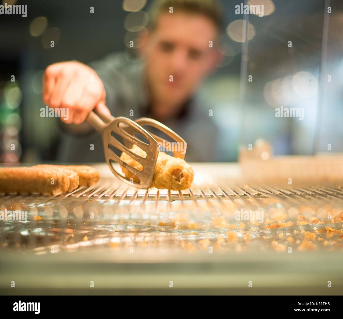 A Uk fast food take away with worker reaching for battered fish and ...