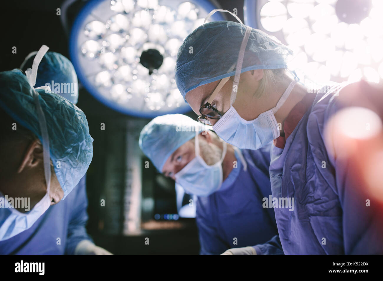 Concentrated female surgeon performing surgery with her team in ...