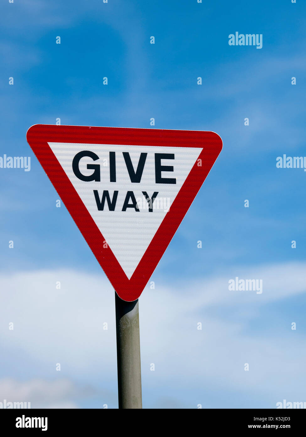Give Way Sign set against a blue sky, with some light white clouds ...
