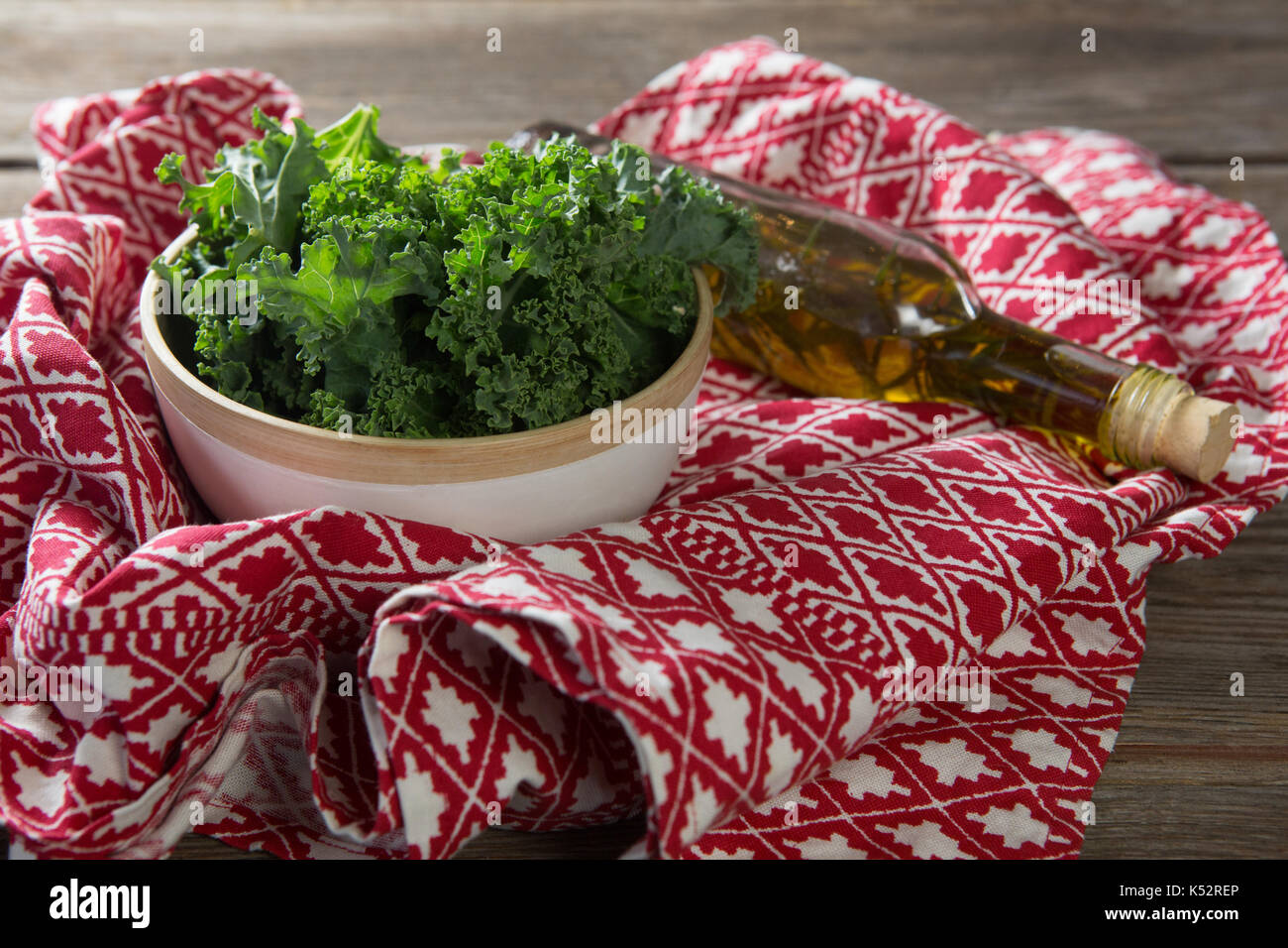 High angle view of fresh kale in bowl with oil bottle and fabric on ...