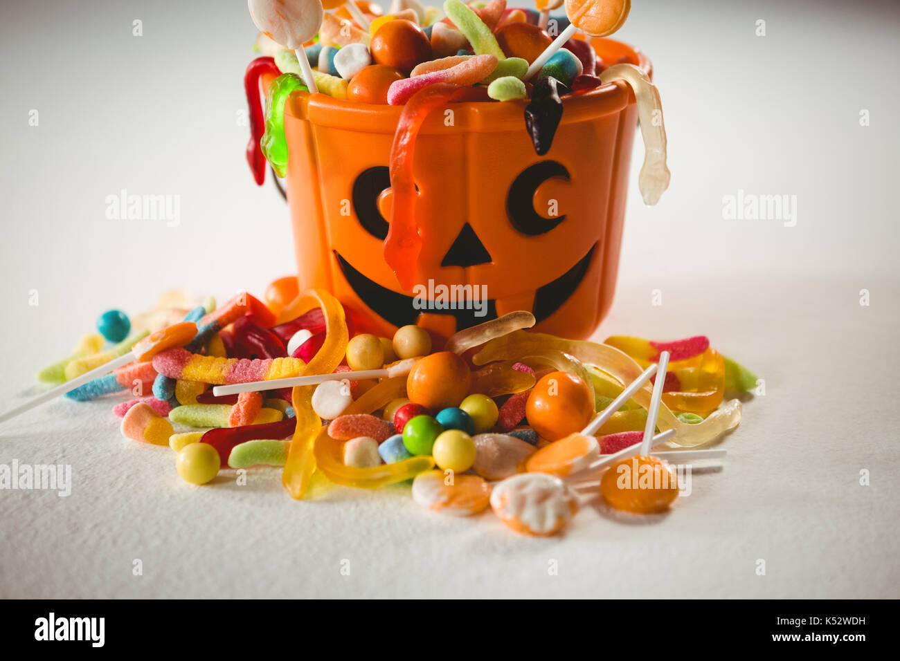 Orange bucket with various sweet food during Halloween over white ...