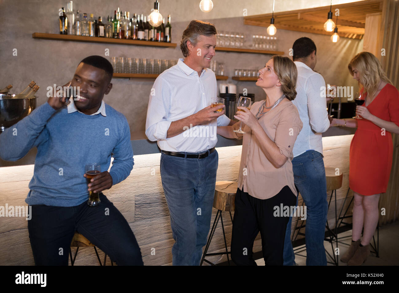 Friends interacting while having drinks at counter in restaurant Stock ...