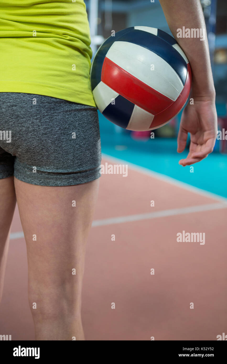Rear view of female player standing with volleyball in the court Stock ...
