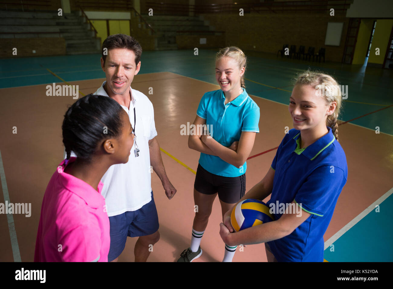 Volleyball coach talking to female players in court Stock Photo - Alamy