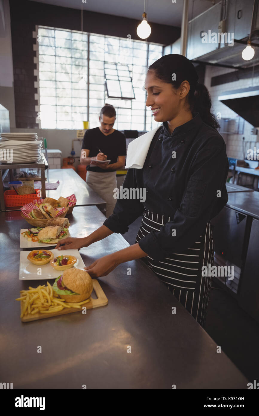 Young waitress arranging plate with food at counter in cafe Stock Photo ...