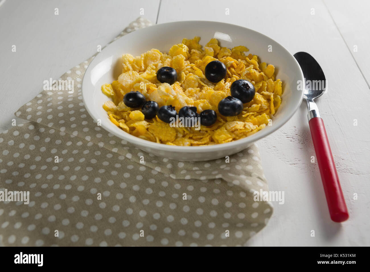 Wheaties cereal and blueberry in bowl with table cloth and spoon on ...