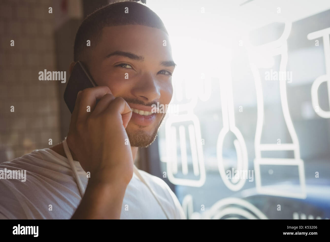 Portrait of waiter talking on mobile phone by window in cafe Stock ...