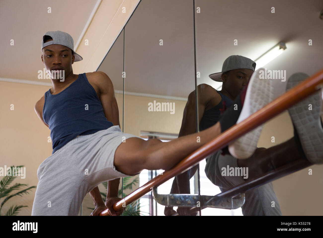 Male dancer stretching leg by mirror on barre in dance studio Stock ...