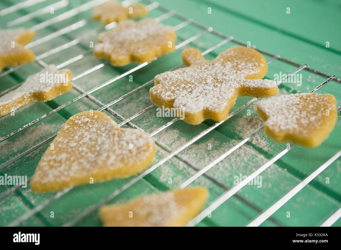 High angle view of powdered sugar on cookies over cooling rack at table ...