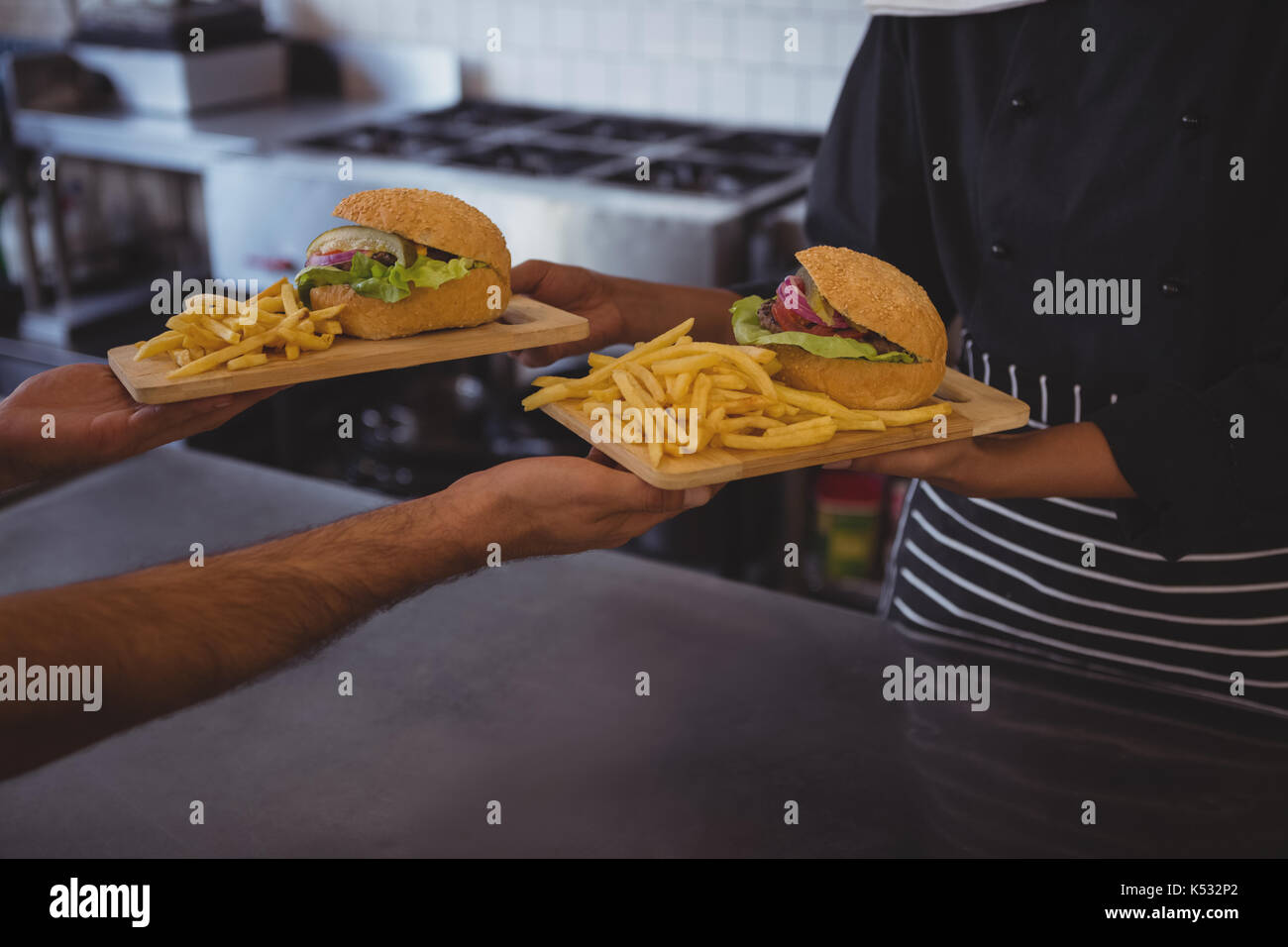 Mid section of waitress giving food to coworker while standing in cafe ...