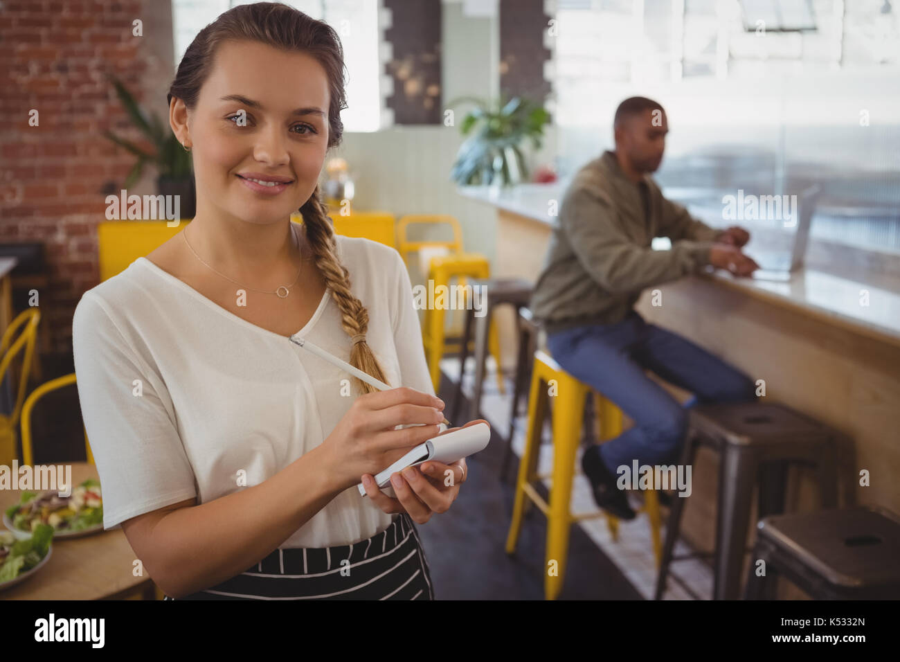 Portrait of waitress taking order while standing by businessman at cafe ...