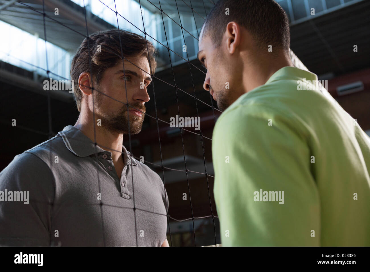 Aggressive male volleyball players looking each other through net at ...