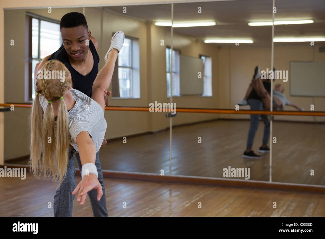 Dancers looking each other by mirror at dance studio Stock Photo - Alamy