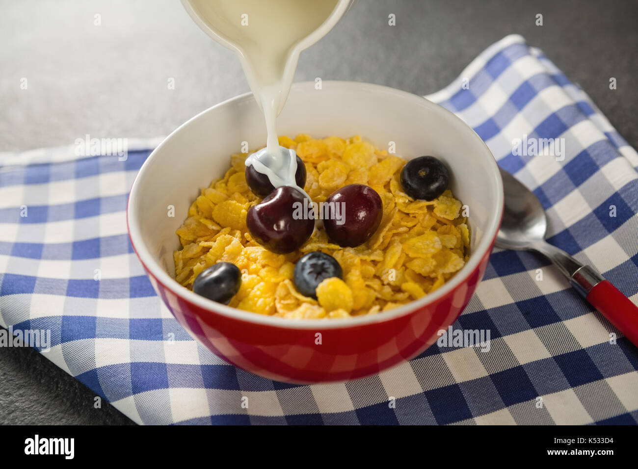Milk being poured into bowl of wheaties cereal on black background ...