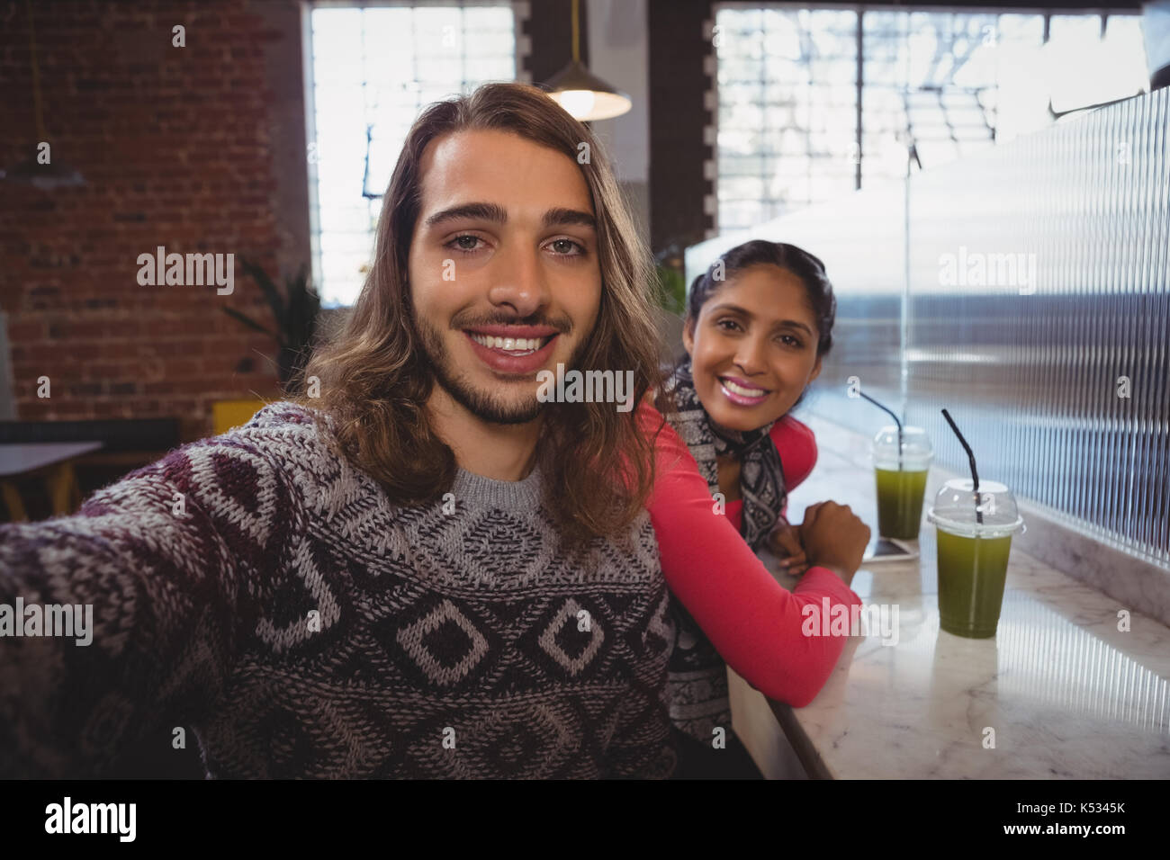Portrait of happy young man with friend at counter in cafe Stock Photo ...