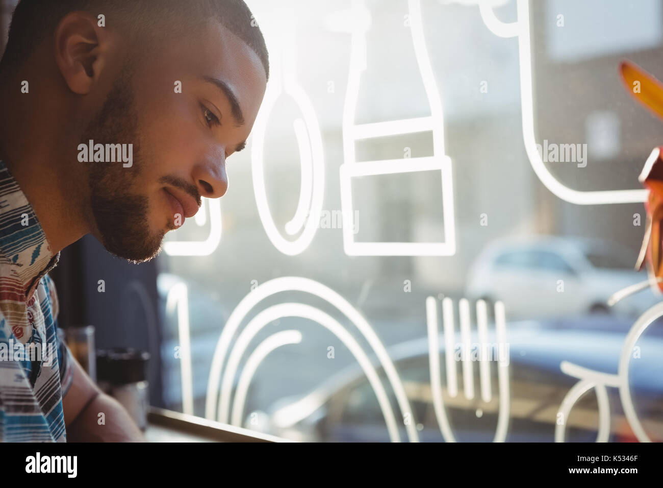 Close-up of young man looking down by window in cafe Stock Photo - Alamy