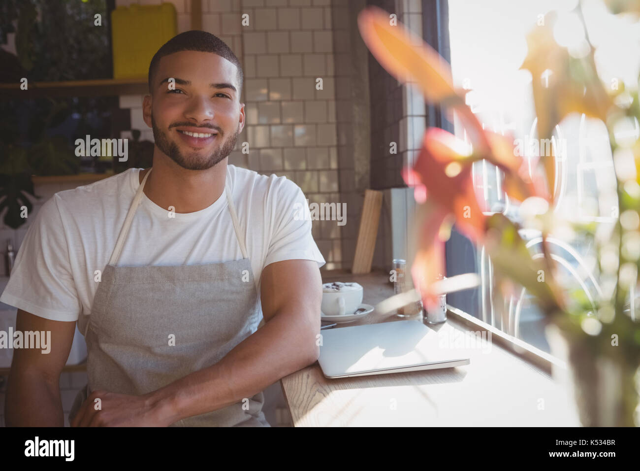 Portrait of smiling waiter at window sill in cafe Stock Photo - Alamy